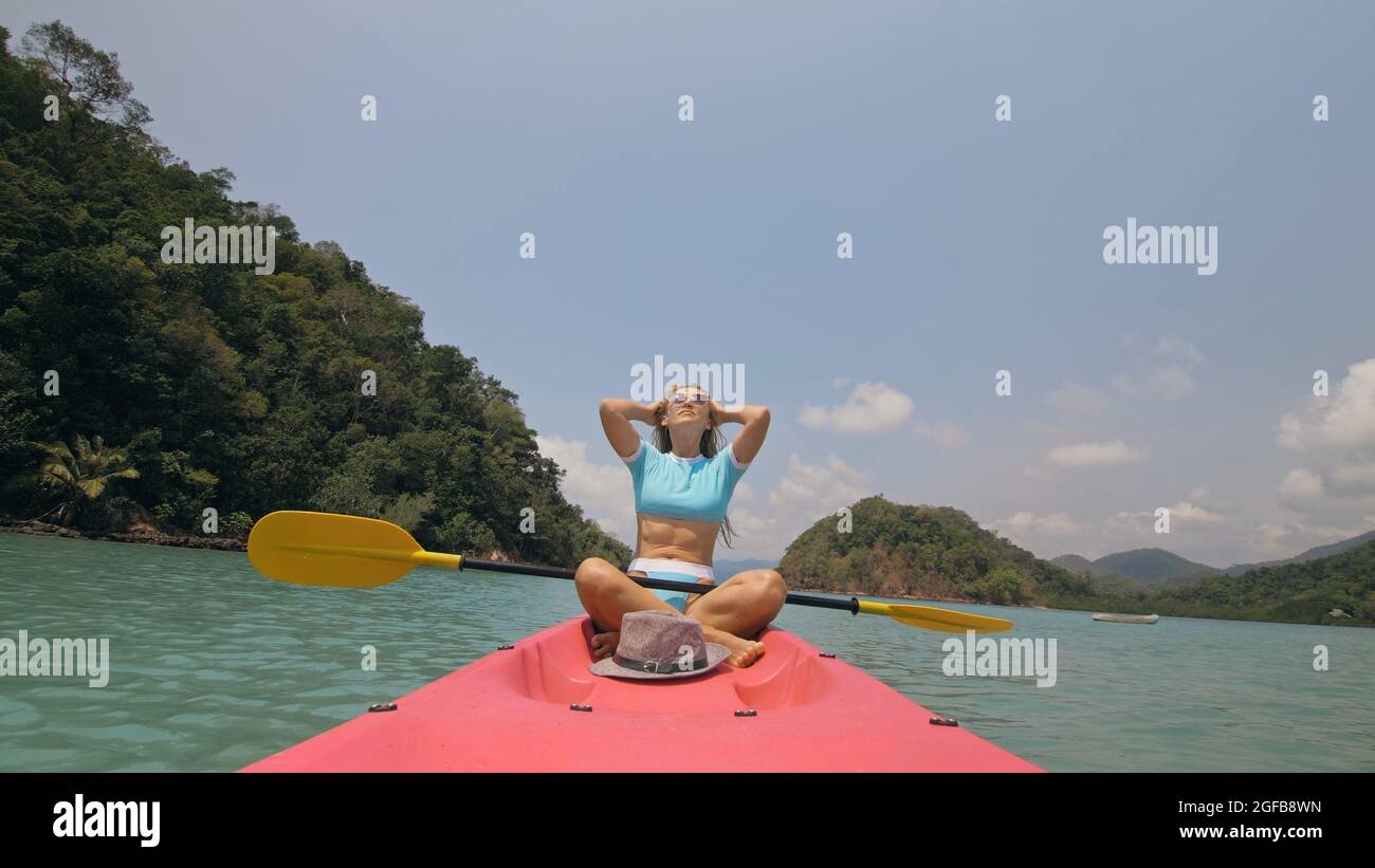 Pretty young blonde woman in stylish swimsuit and sunglasses sits on ...