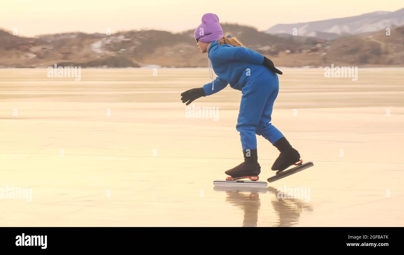 The girl train on ice speed skating. The child skates in the winter in ...