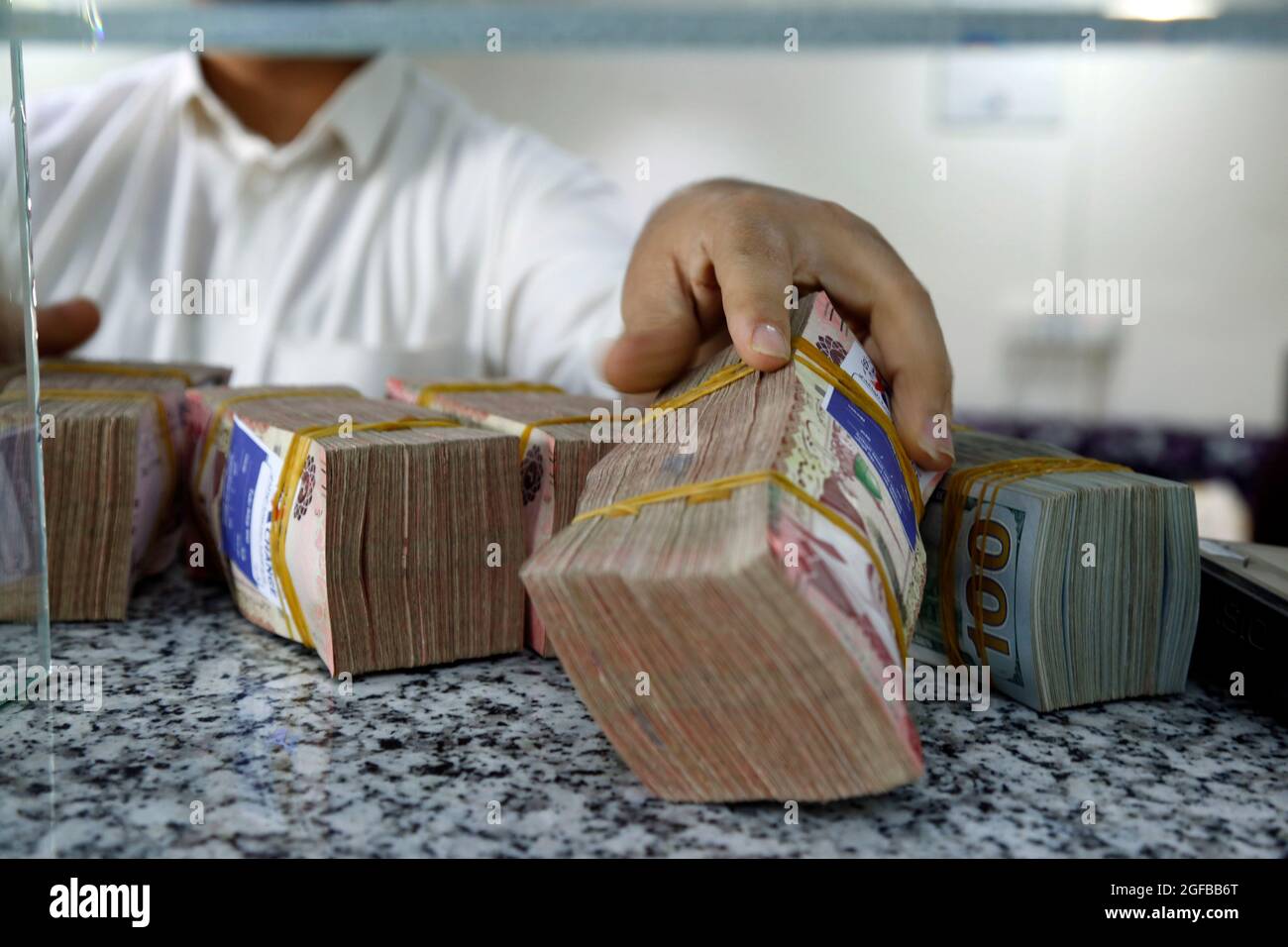 Sanaa. 24th Aug, 2021. A teller counts cash inside a foreign exchange ...