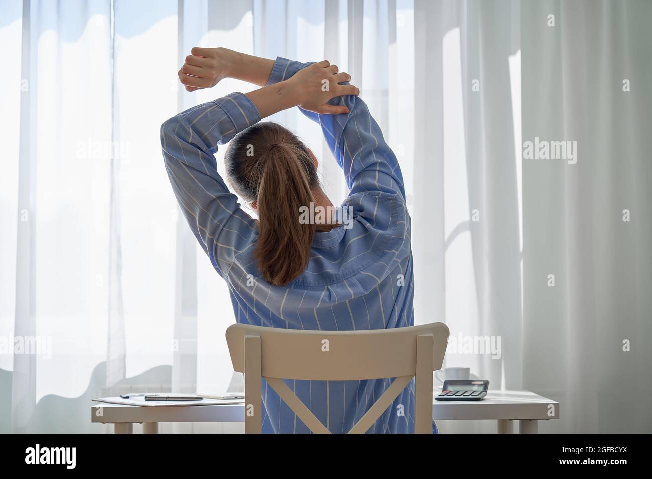 Back view of female stretching. Back pain due to remote work. Negative ...