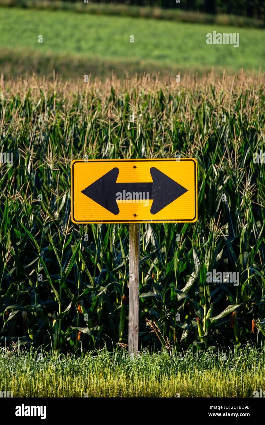 Road sign with arrows pointing in opposite directions next to a ...