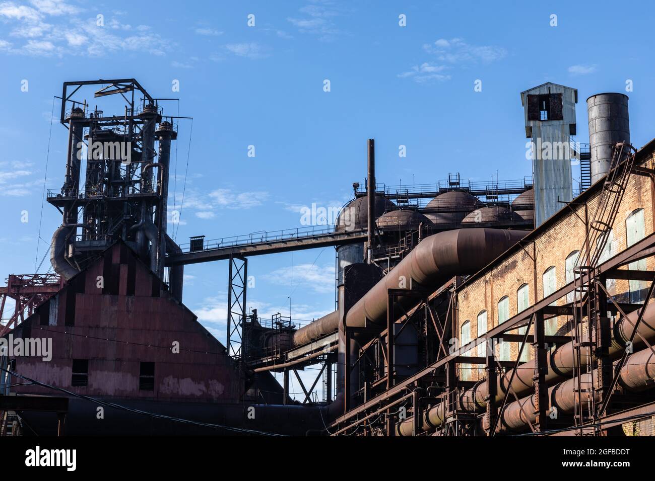 Abandoned steel mill facility, old brick warehouse ringed in huge tubes ...