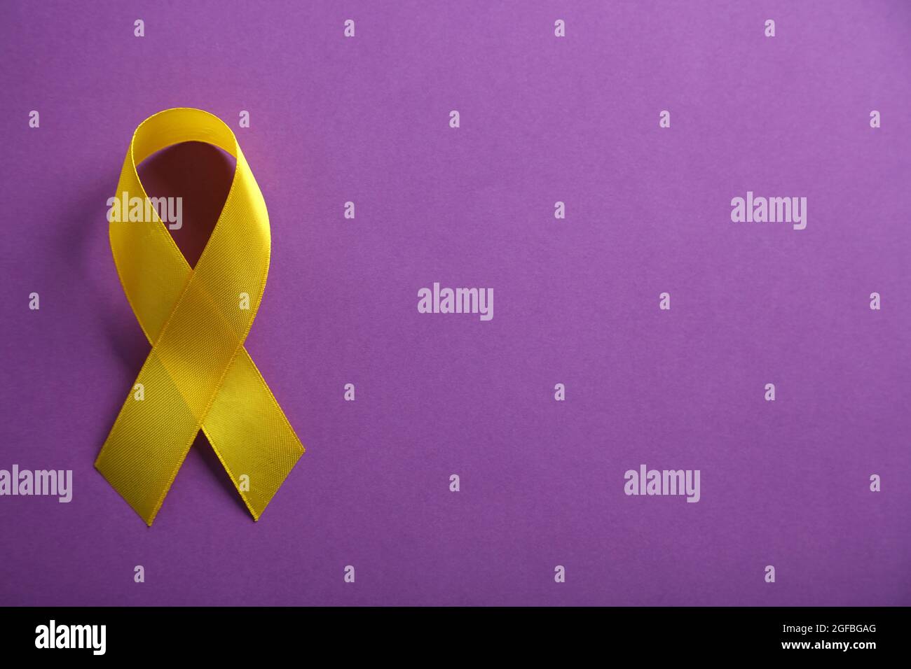 Yellow ribbon on purple background Stock Photo - Alamy