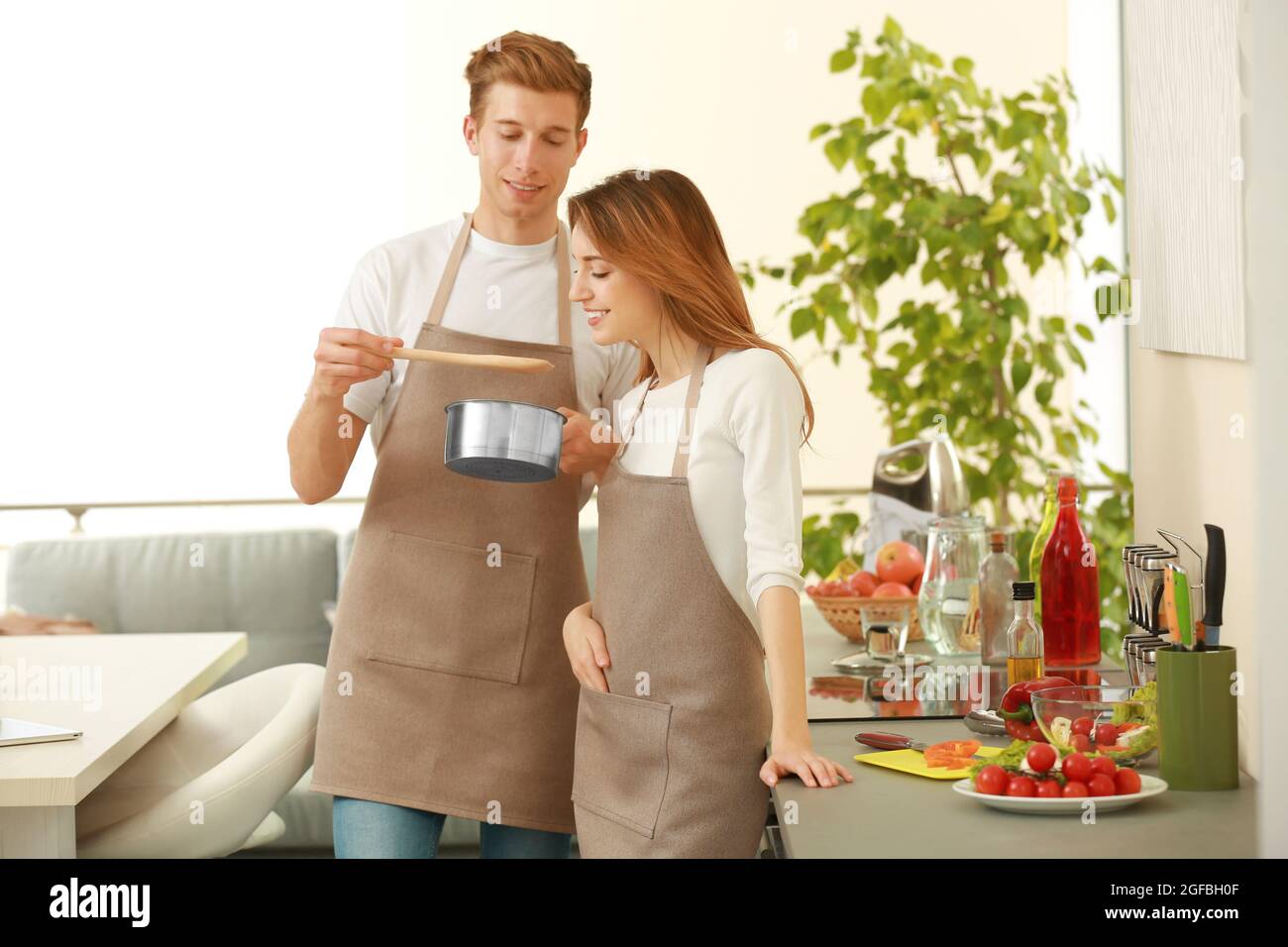 Couple in aprons cooking in kitchen Stock Photo - Alamy