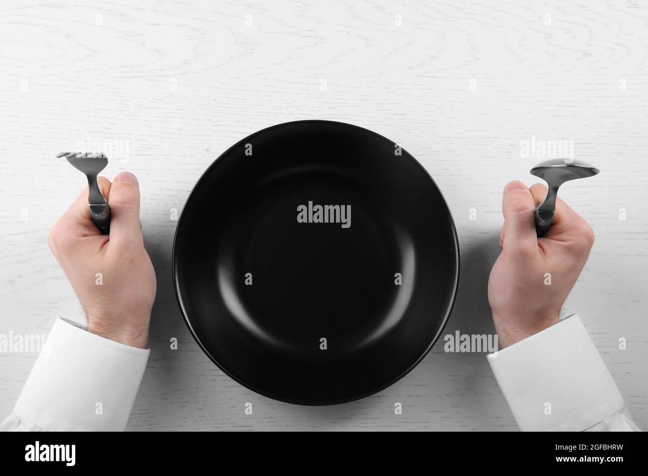 Man holding fork and spoon with empty plate. Hunger concept Stock Photo ...