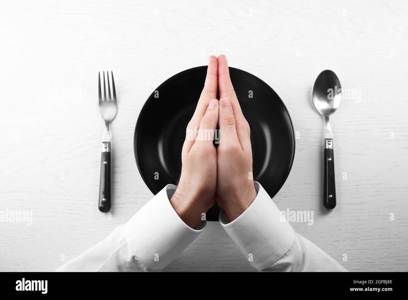 Man holding hands over empty plate. Hunger concept Stock Photo - Alamy