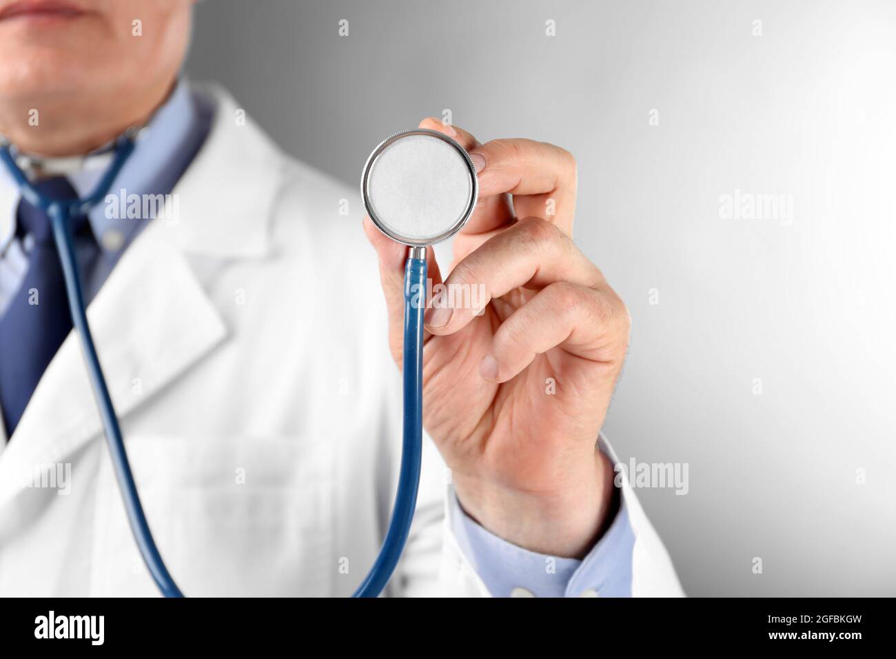 Professional doctor with stethoscope on grey background Stock Photo - Alamy
