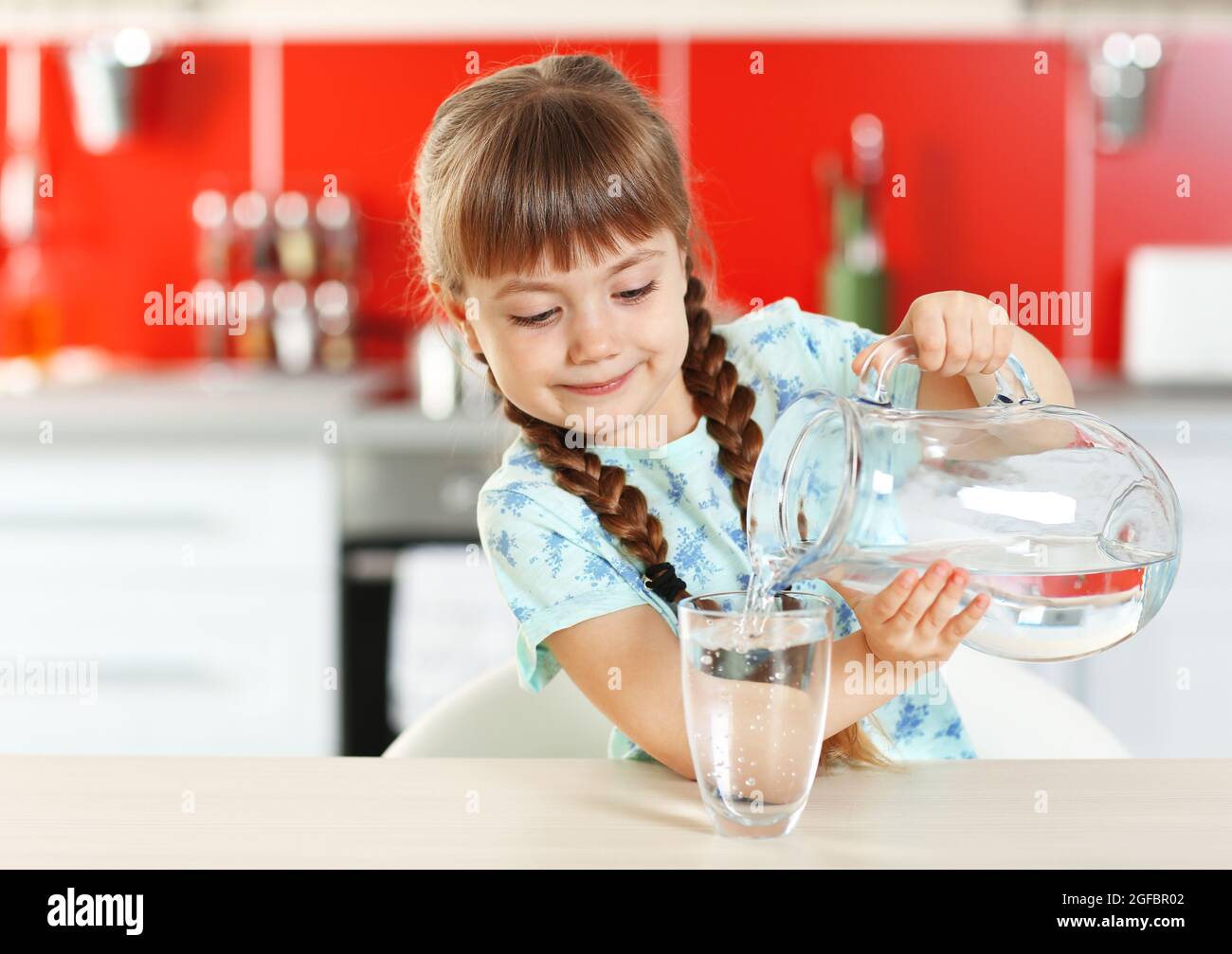 Adorable little girl pouring water in kitchen Stock Photo - Alamy