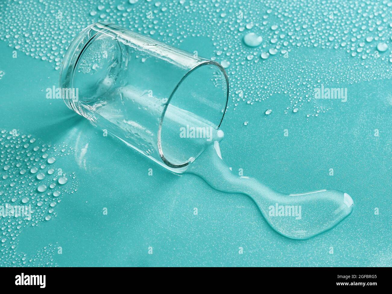 Overturned shot glass on turquoise background Stock Photo - Alamy