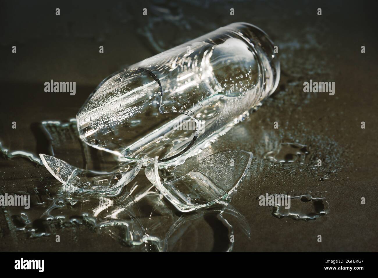 Broken overturned glass on gray background Stock Photo - Alamy