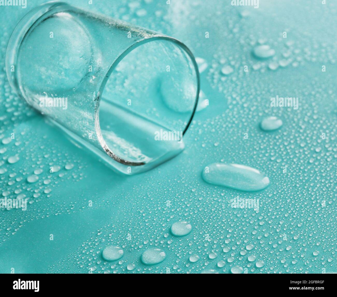 Overturned shot glass on turquoise background Stock Photo - Alamy