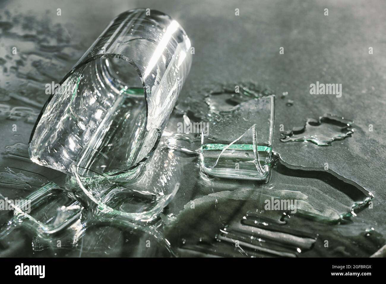 Broken overturned glass on gray background Stock Photo - Alamy