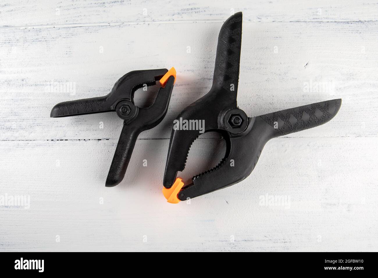 Black plastic clamps on a white wooden background Stock Photo - Alamy