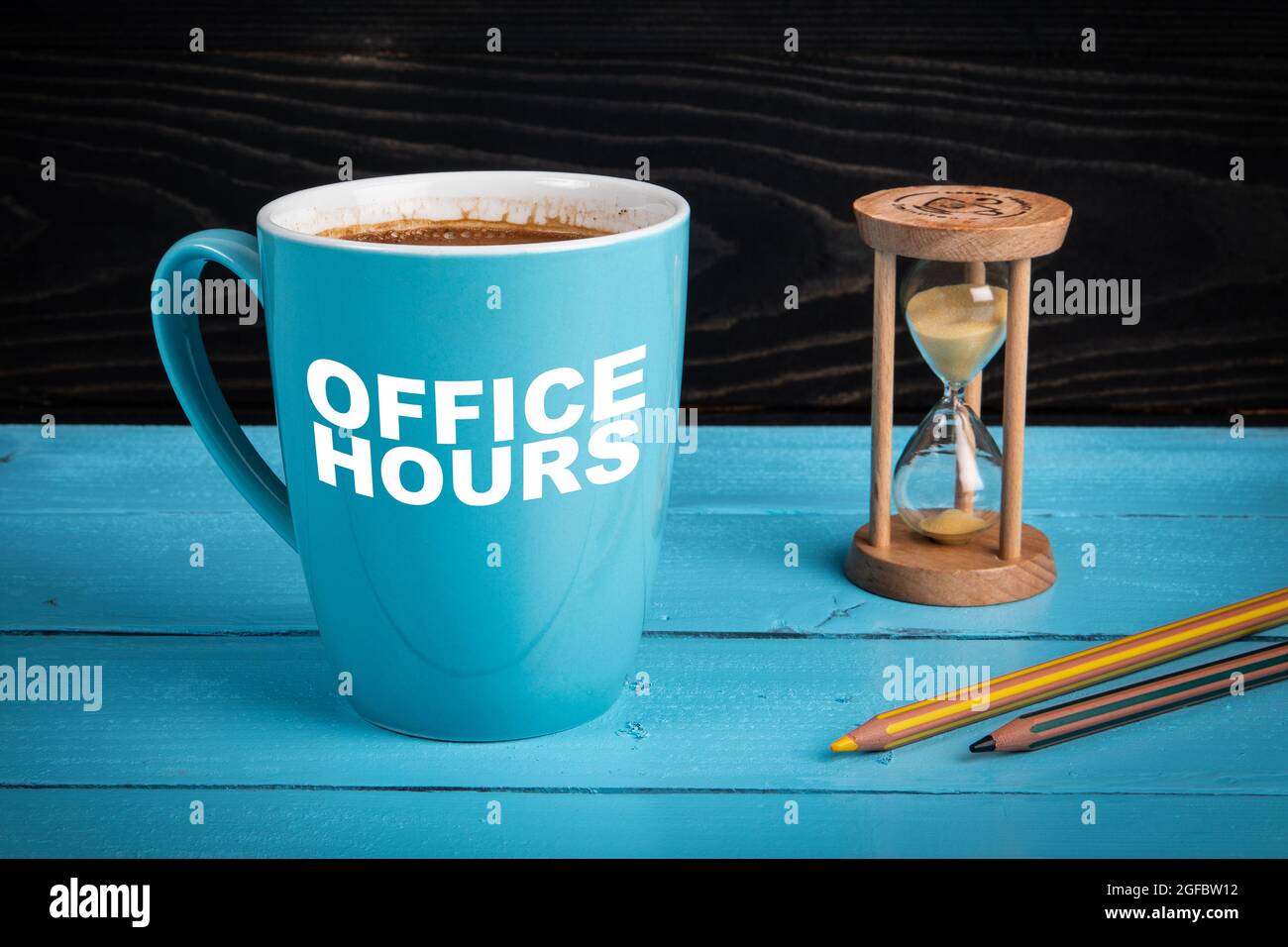 Office Hours. Coffee mug, hourglass and pencils on the office desk ...