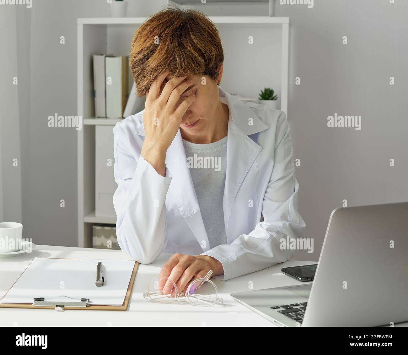 Female healthcare worker having headache. Tired and stressed doctor ...
