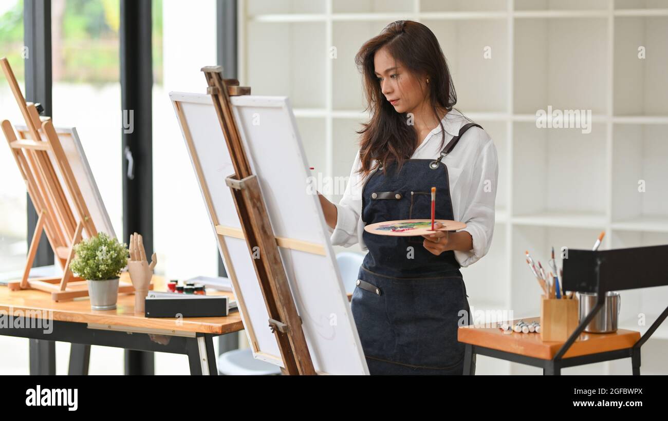 Art school, creative female art student painting on her masterpiece ...