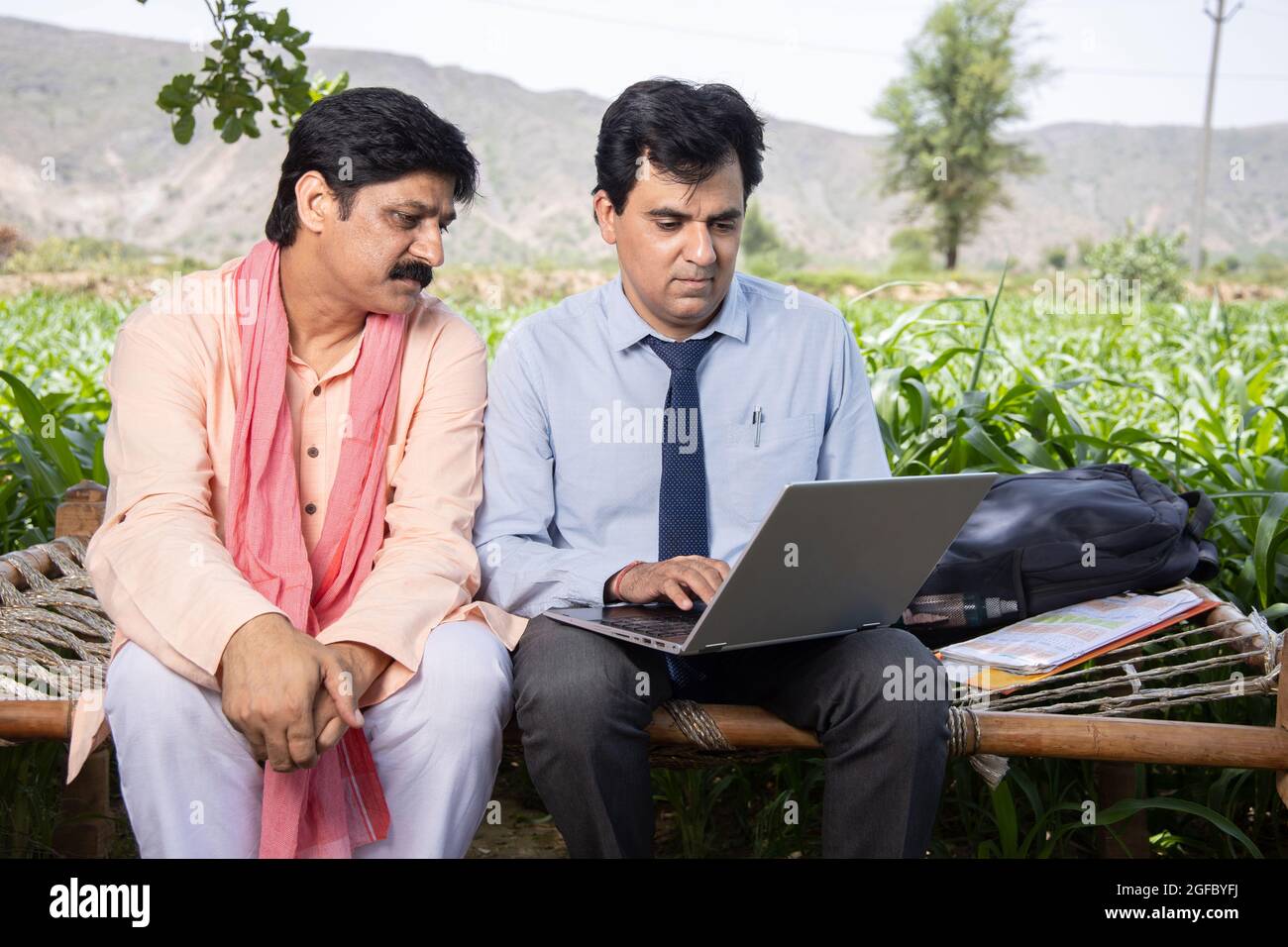 Rural indian male farmer with agronomist or banker use laptop sitting ...