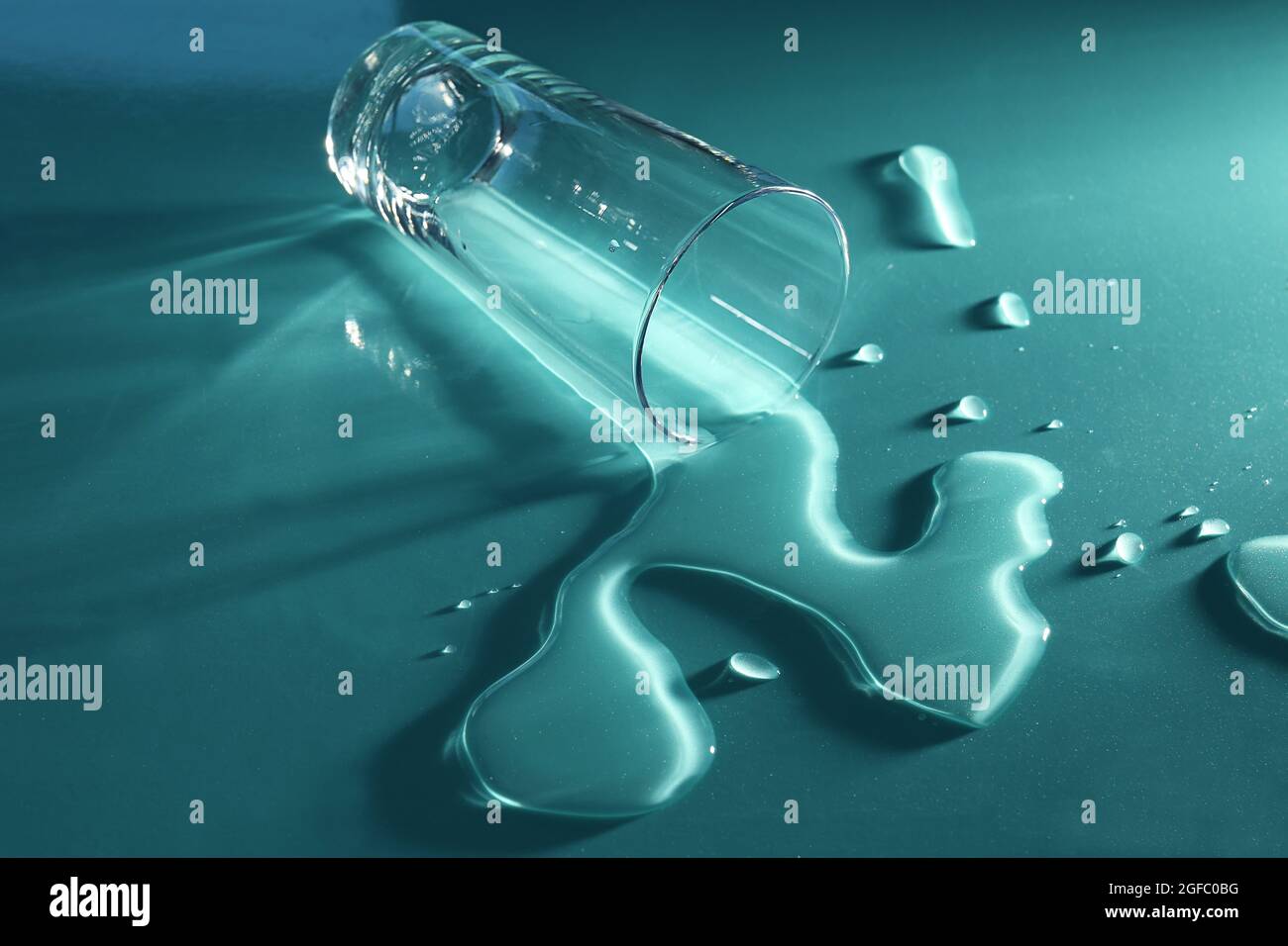 Glass of water spilled on blue background Stock Photo - Alamy