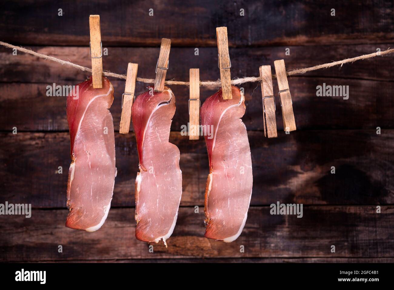 Presentation of slices of bacon hanging by a thread with tweezers Stock ...