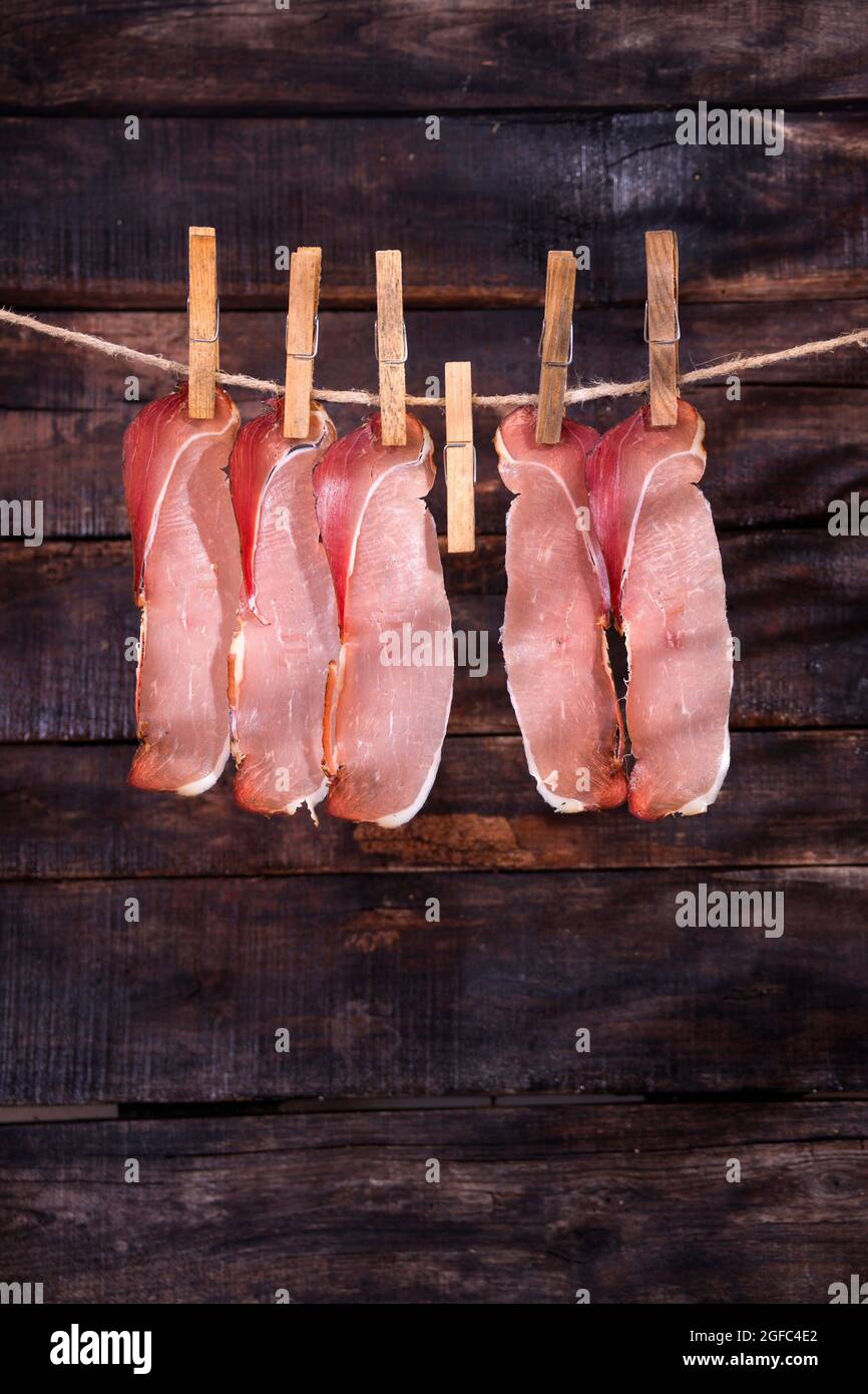 Presentation of slices of bacon hanging by a thread with tweezers Stock ...
