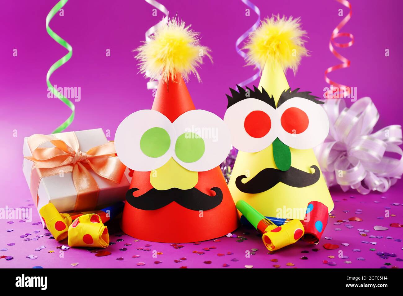 Funny party hats with blowers on color background Stock Photo - Alamy