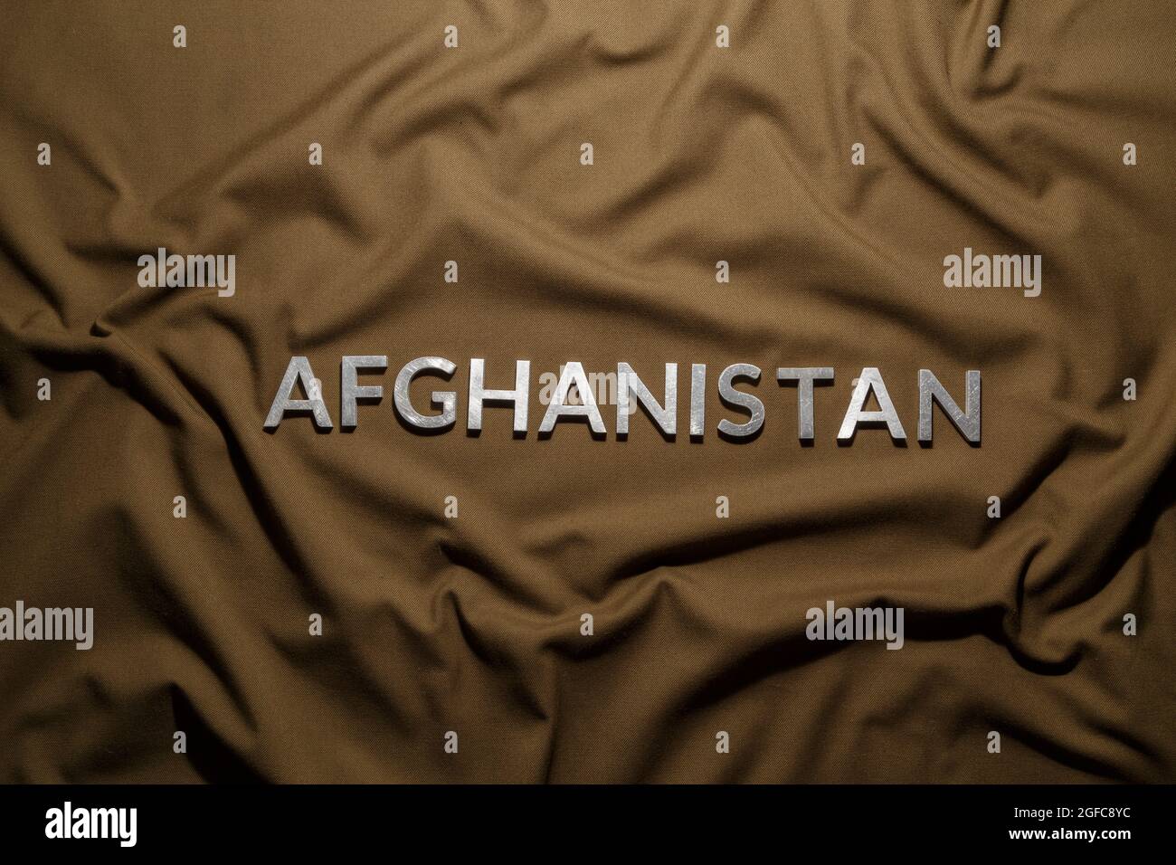 the word afghanistan laid with silver metal letters on crumpled tan ...