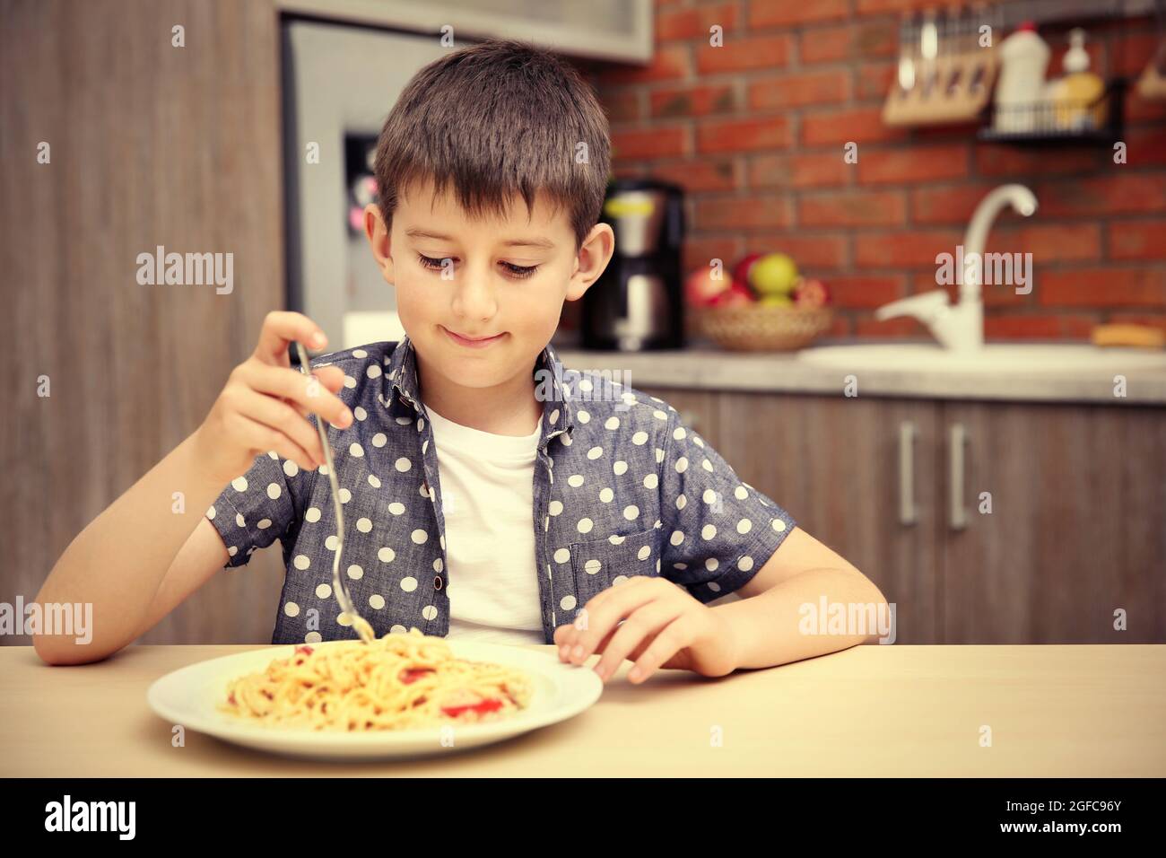 Cute boy eating spaghetti on kitchen Stock Photo - Alamy