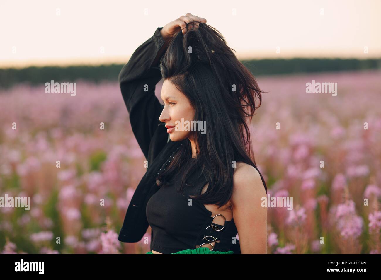 Young brunette woman on blooming Sally flower field. Lilac flowers and ...