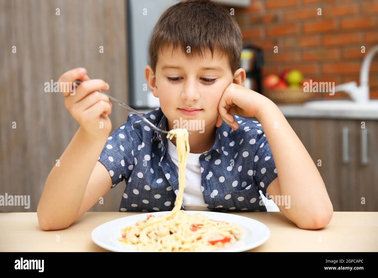 Cute boy eating spaghetti on kitchen Stock Photo - Alamy