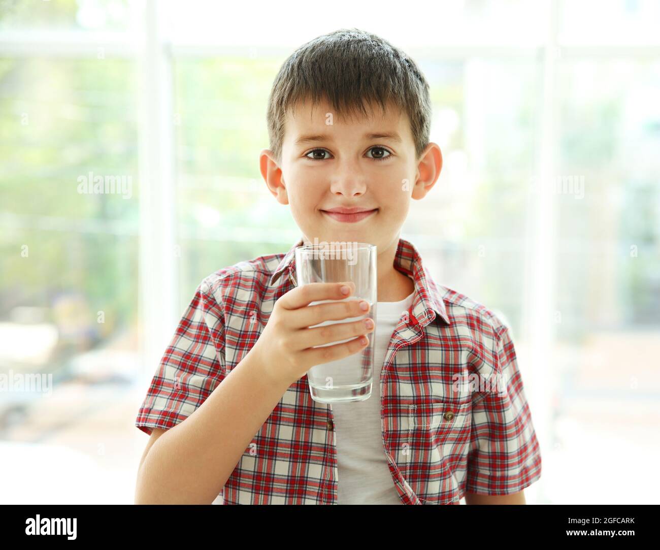 Cute boy drinking water on kitchen Stock Photo - Alamy