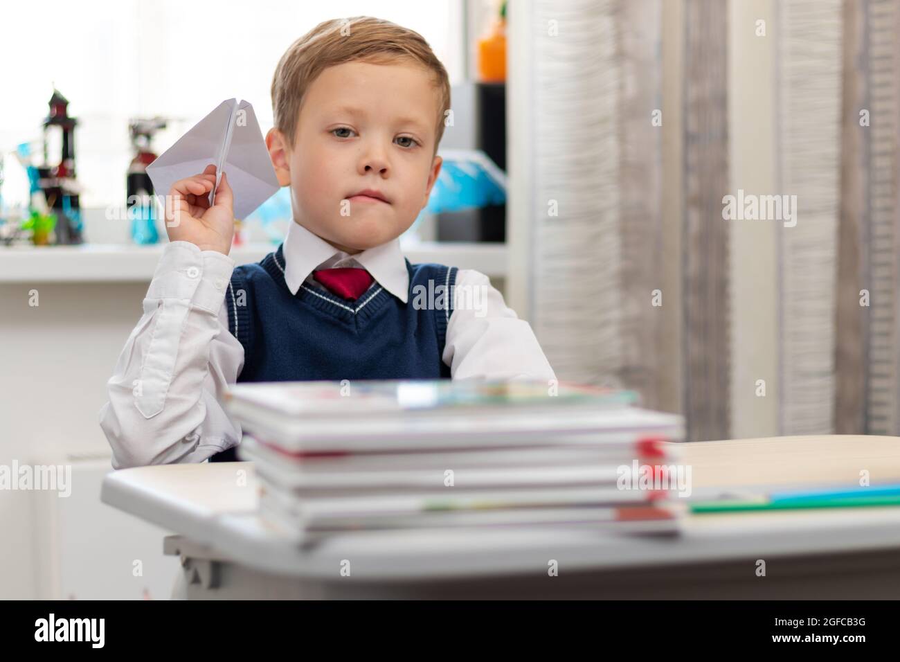 A cute first-grader boy in a school uniform at home while isolated at ...