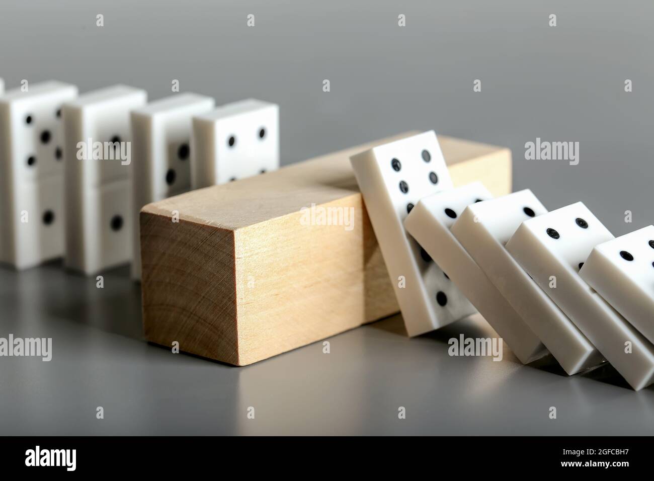 Dominoes and brick block on grey background Stock Photo - Alamy