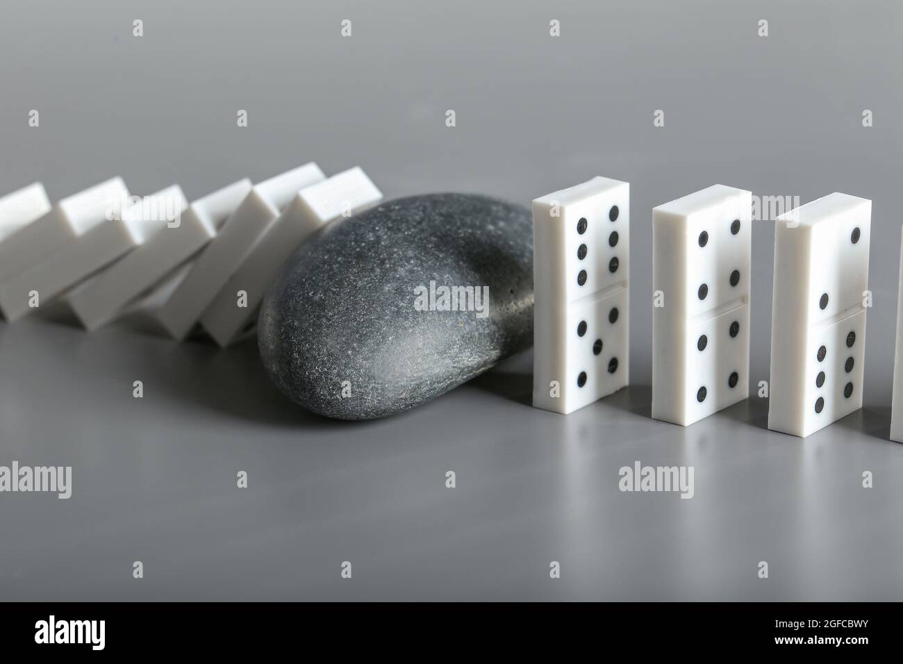 Dominoes and stone on grey background Stock Photo - Alamy