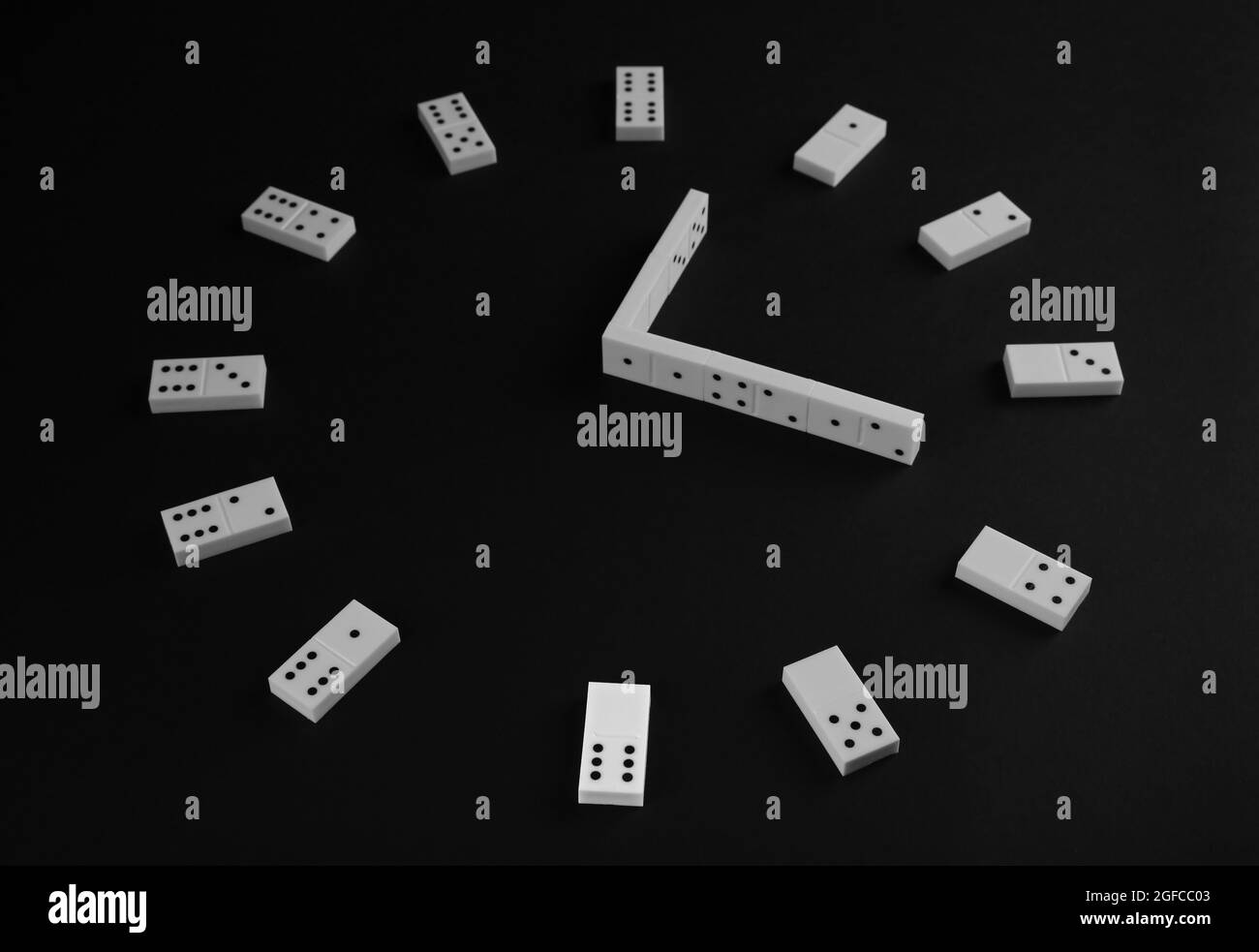 Dominoes in shape of clock on black background Stock Photo - Alamy