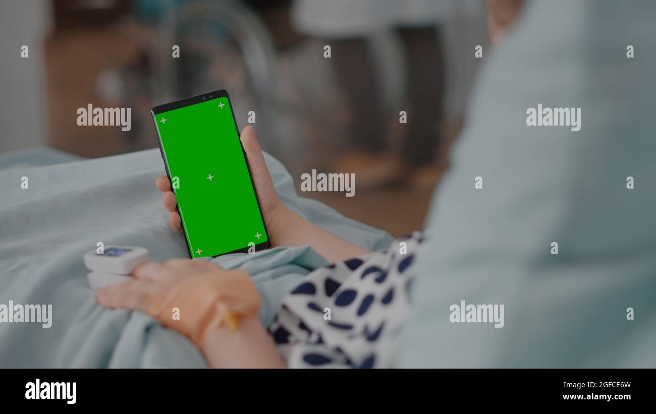 Sick girl holding mock up green screen chroma key phone with isolated ...