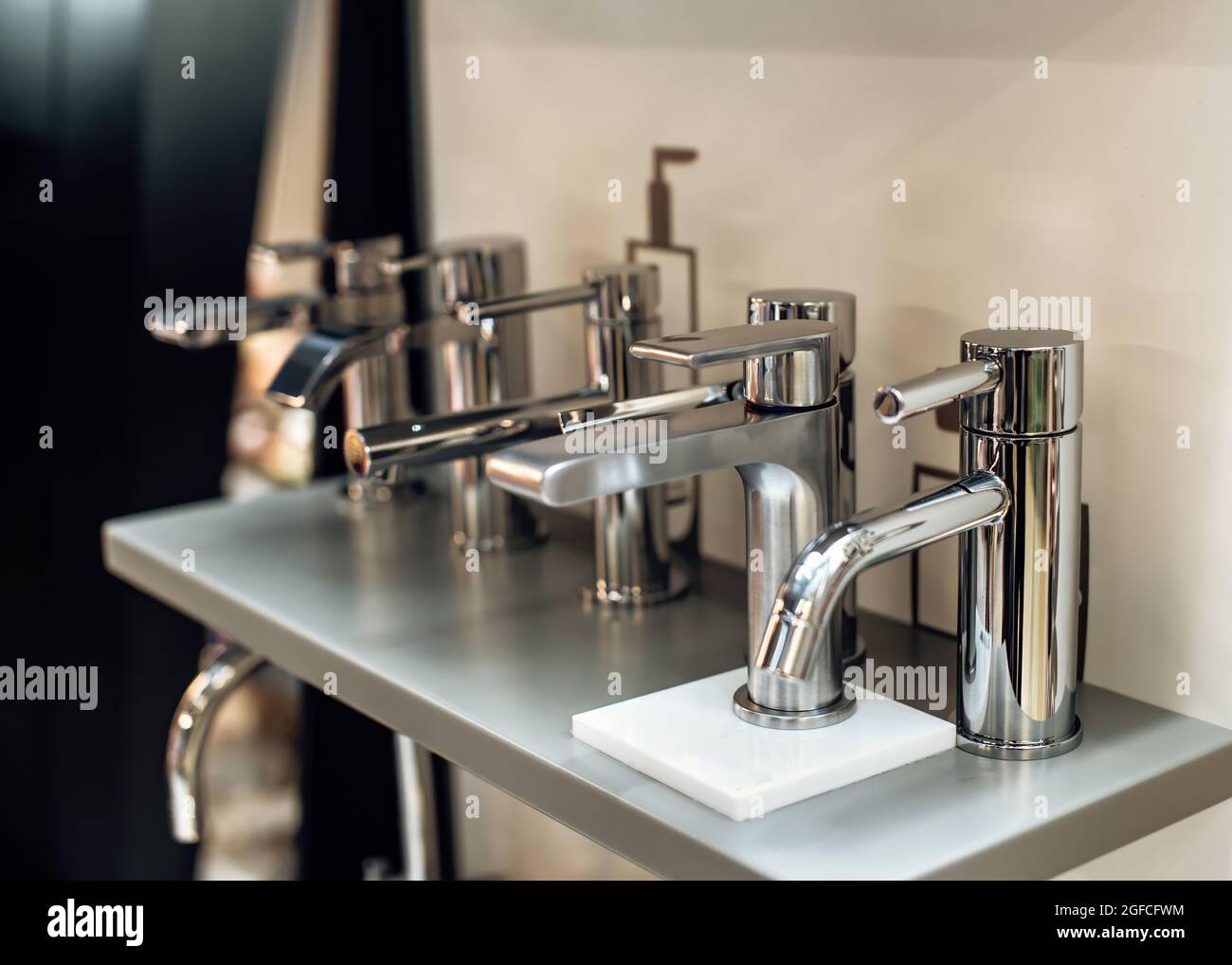 Group of modern stylish water taps for bathroom in showroom. Rows of ...