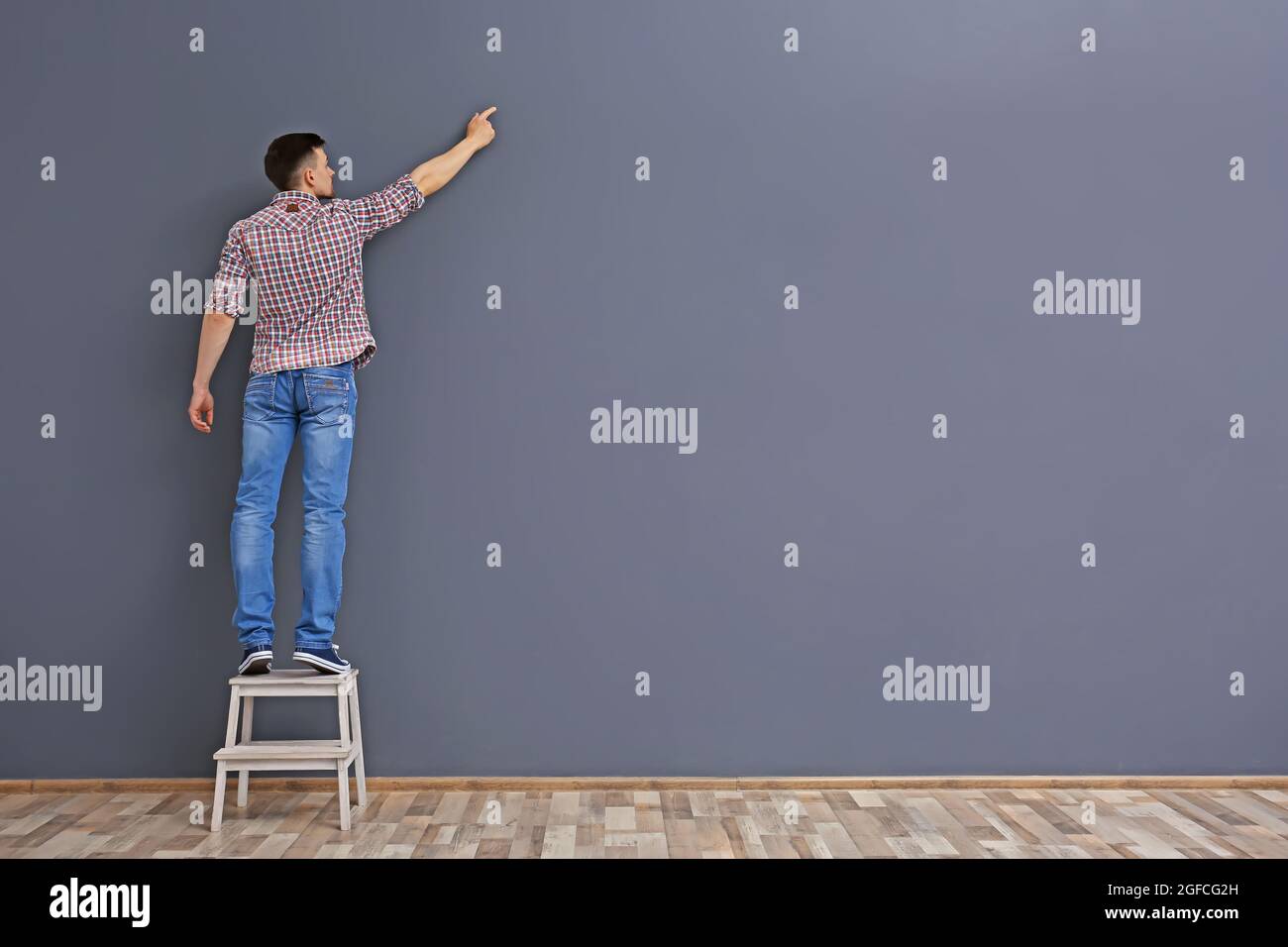Man writing something on grey wall Stock Photo - Alamy