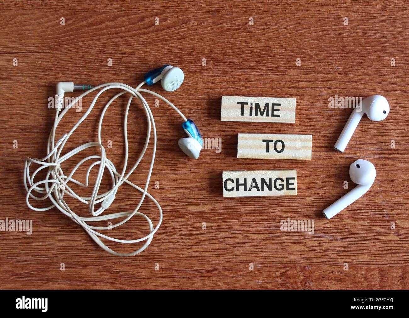 Top view of two types of earphones and wooden cube with text TIME TO ...