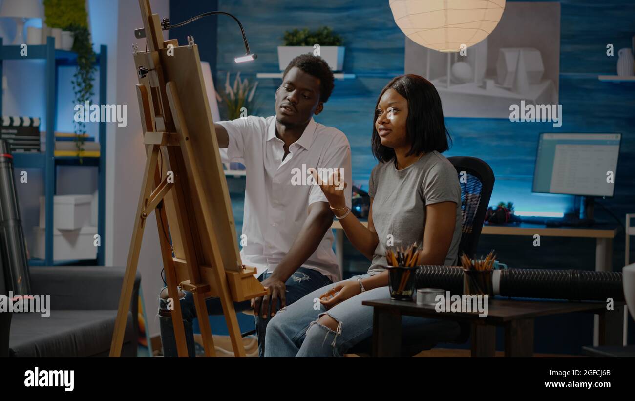 African american artists couple checking art drawing on easel sitting ...