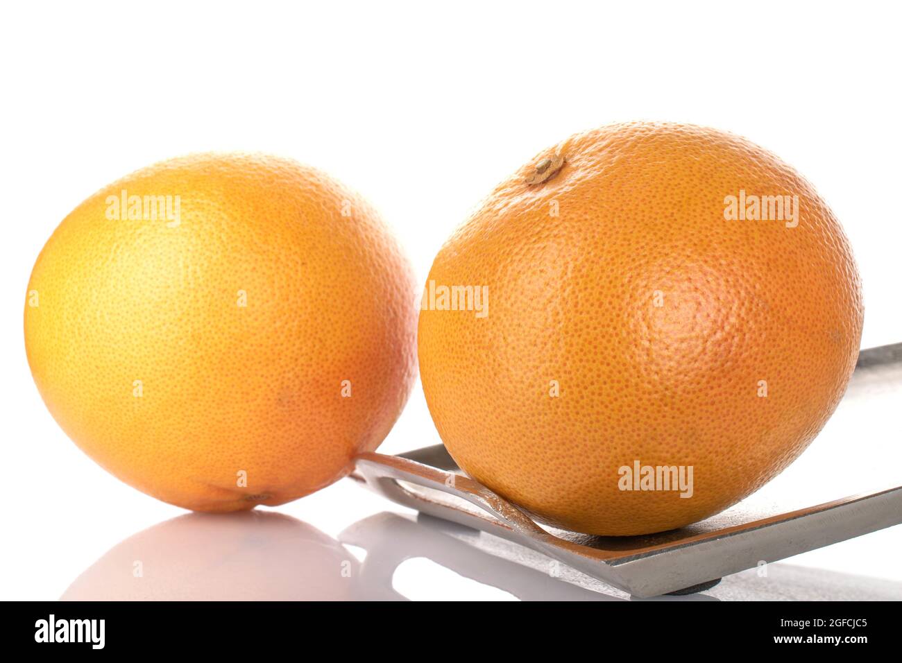Two ripe natural grapefruit with a metal tray, close-up, on a white ...