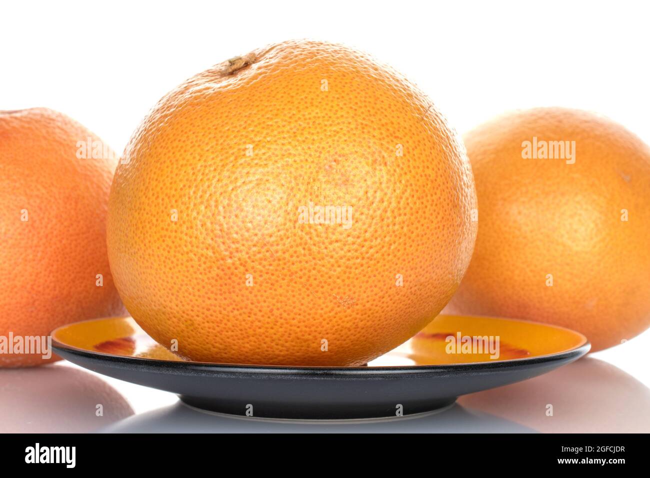 Three ripe natural grapefruit with a saucer, close-up, on a white ...