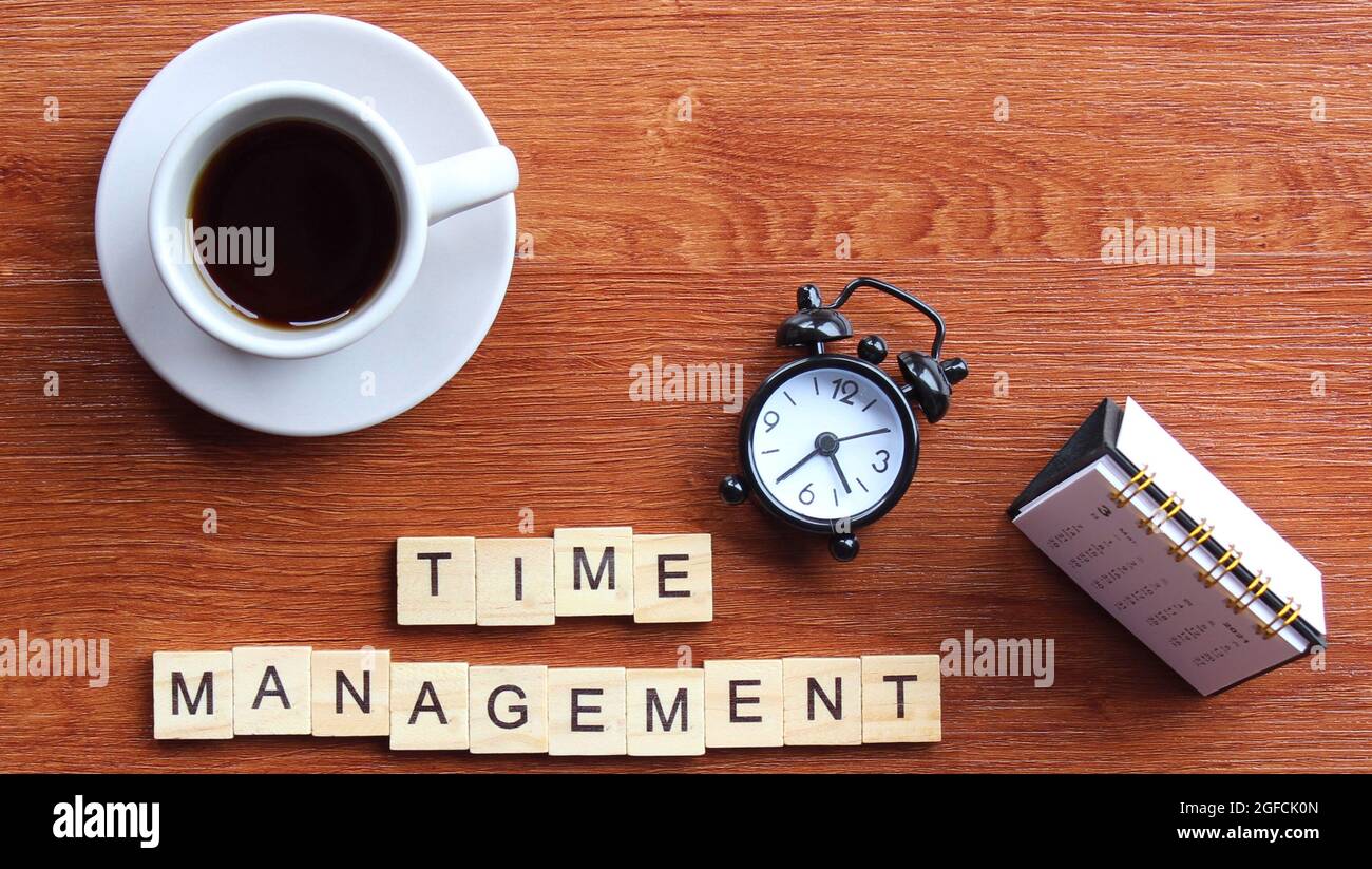 Top view of alarm clock, calendar, cup of coffee and wooden cube with ...
