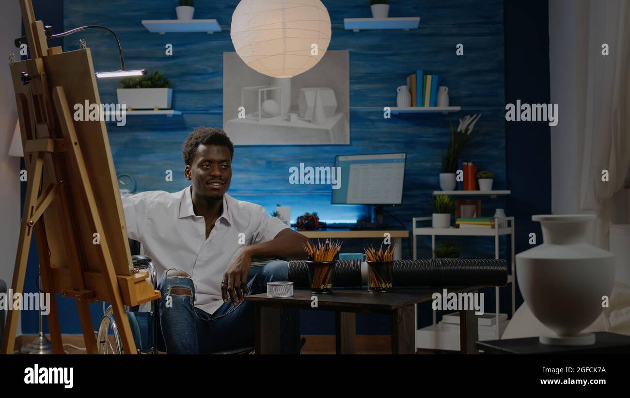 Black person in wheelchair designing vase drawing in artwork studio ...