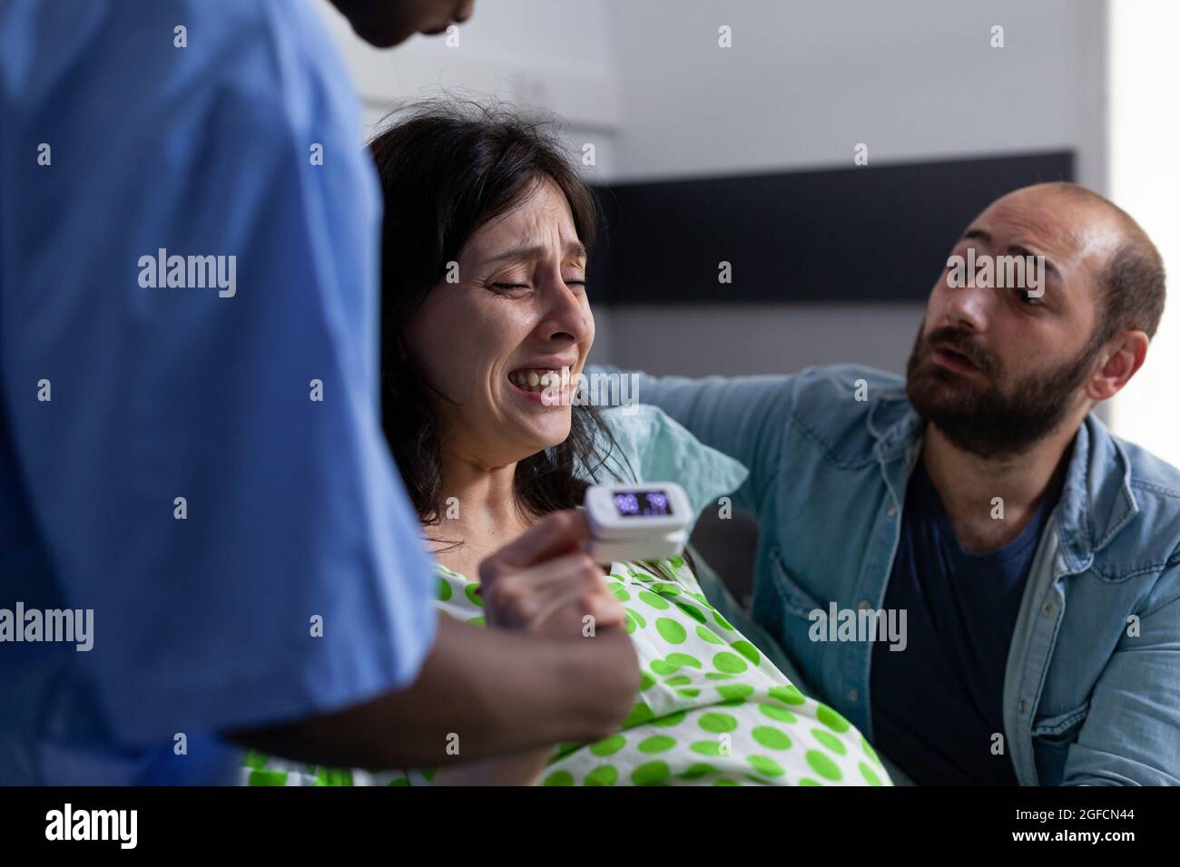 Medical assistant holding hand of pregnant woman sitting in hospital ...