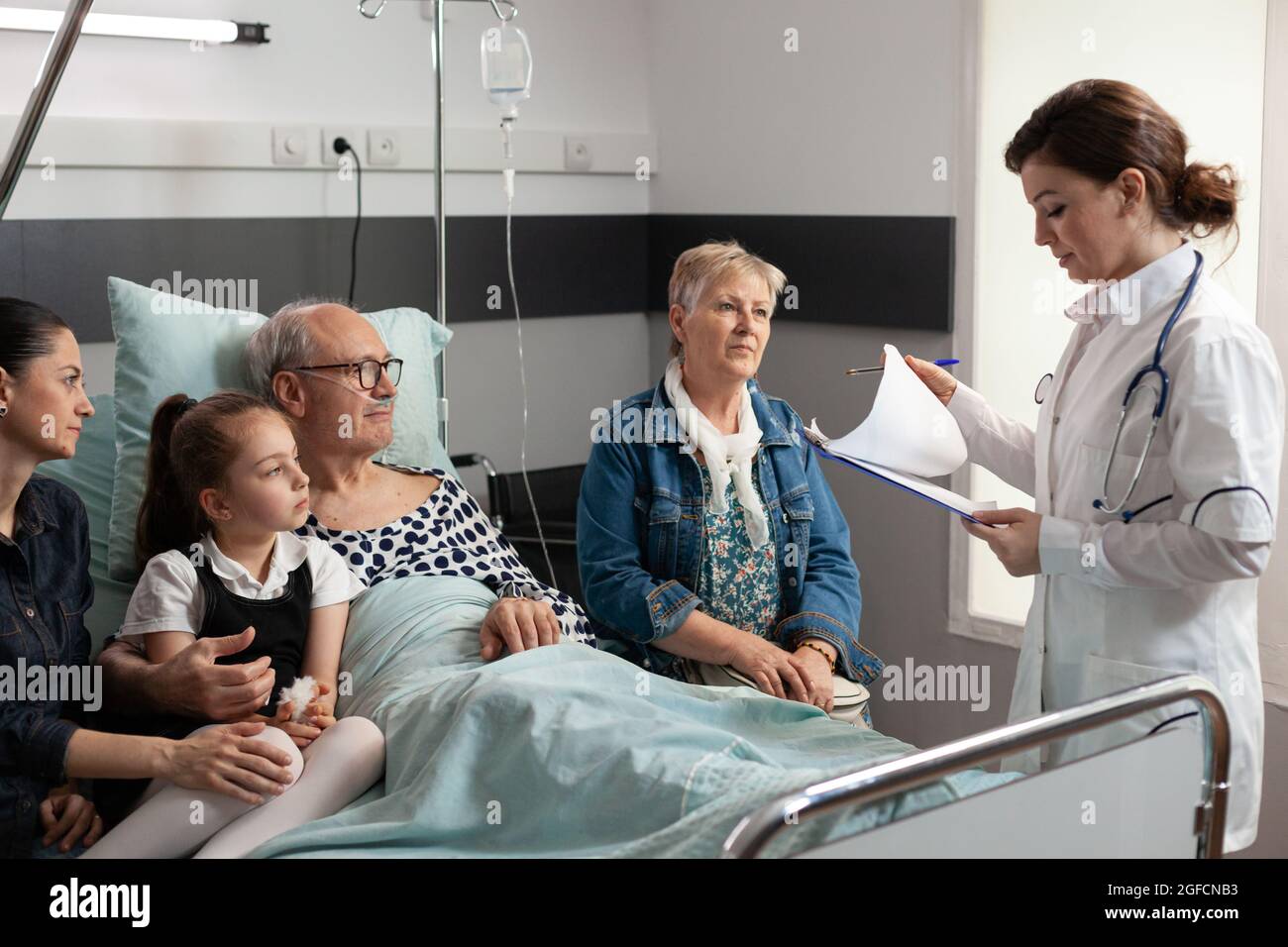 Elderly sick old patient resting in bed with caring family beside him ...