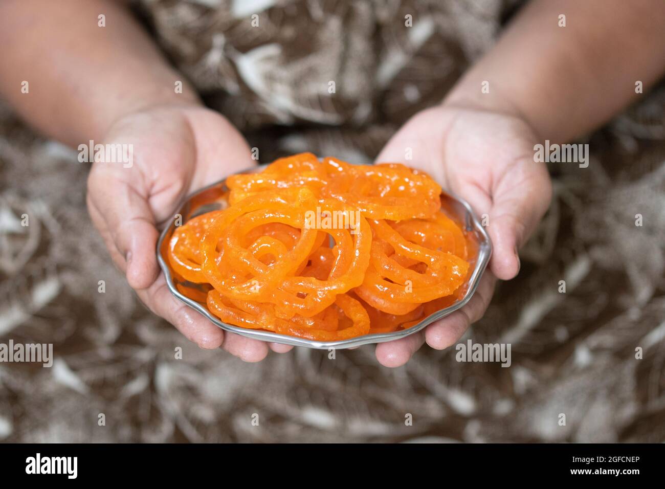 Holding Jalebi and Indian sweet in a steel plate, Satara, Maharashta ...