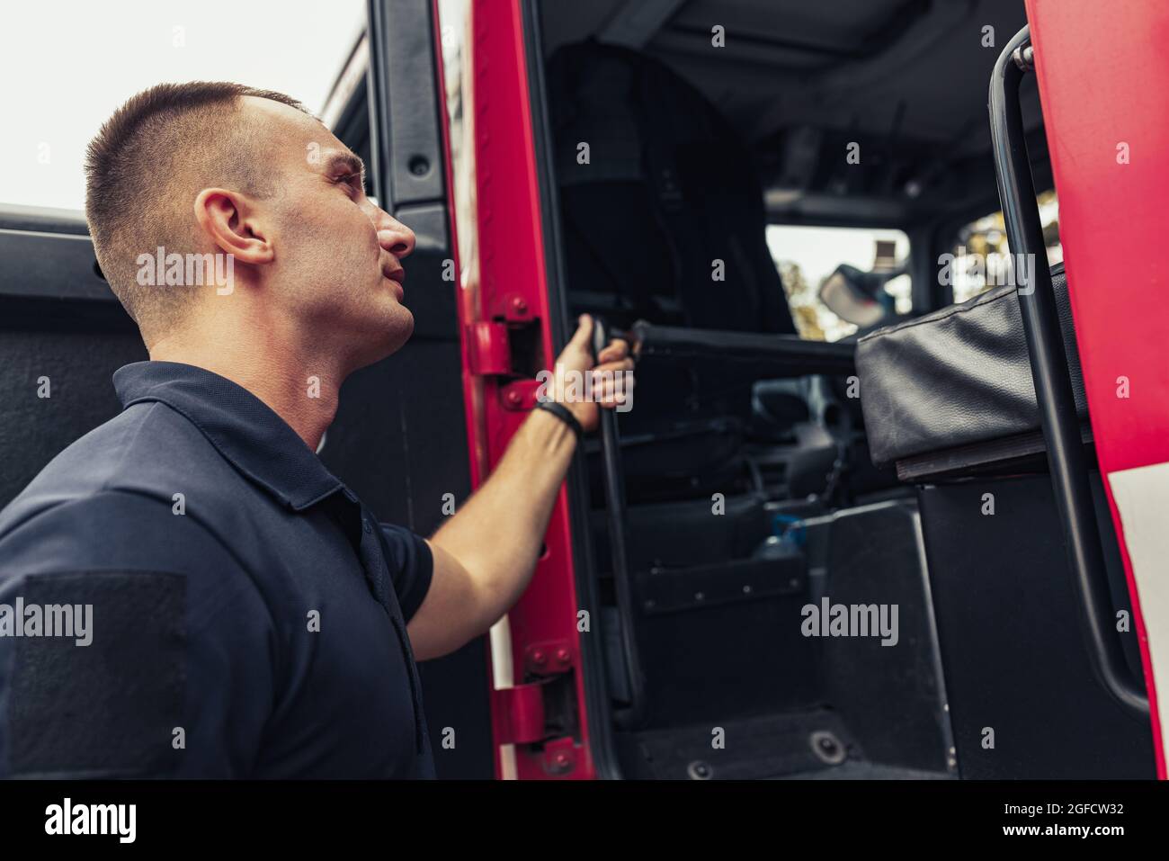 Fireman by fire truck using professional firefighting equipment Stock ...