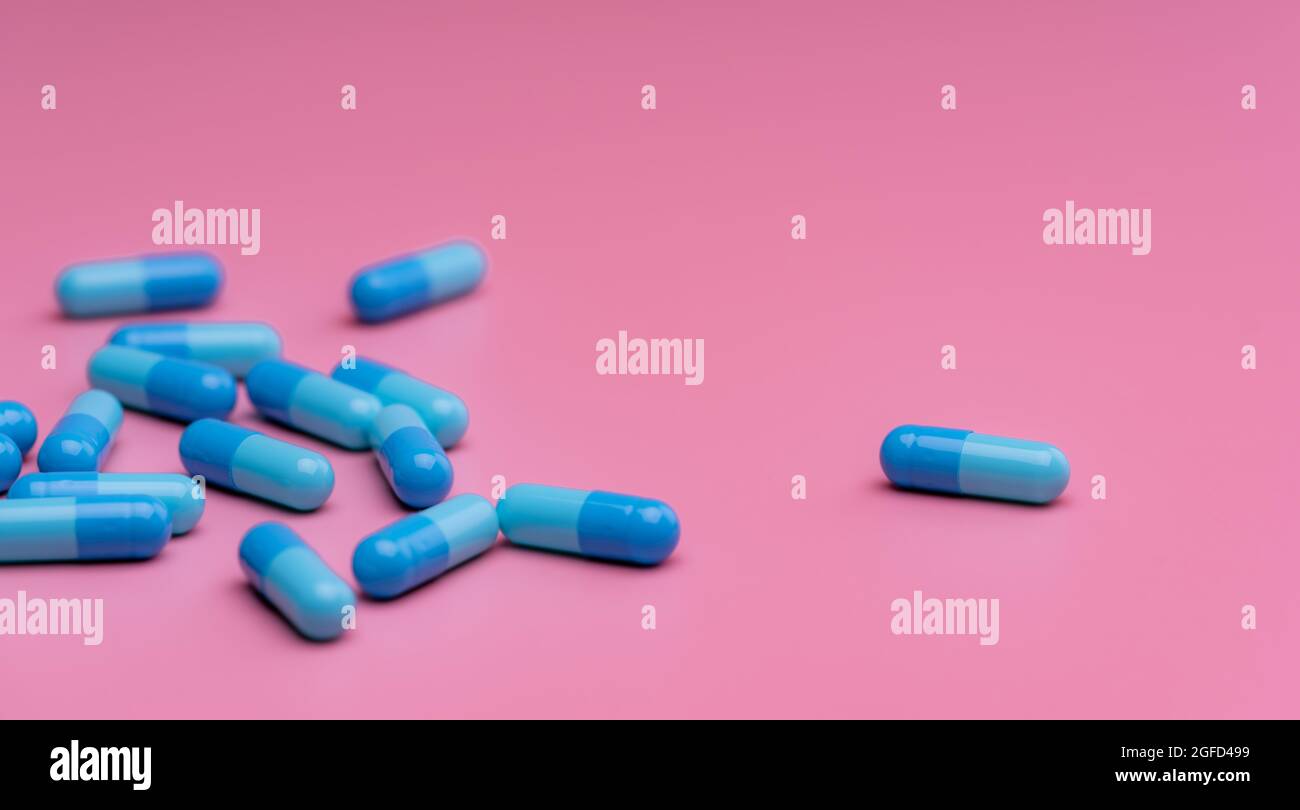 Blue antibiotic capsule pills on pink background. Online pharmacy ...