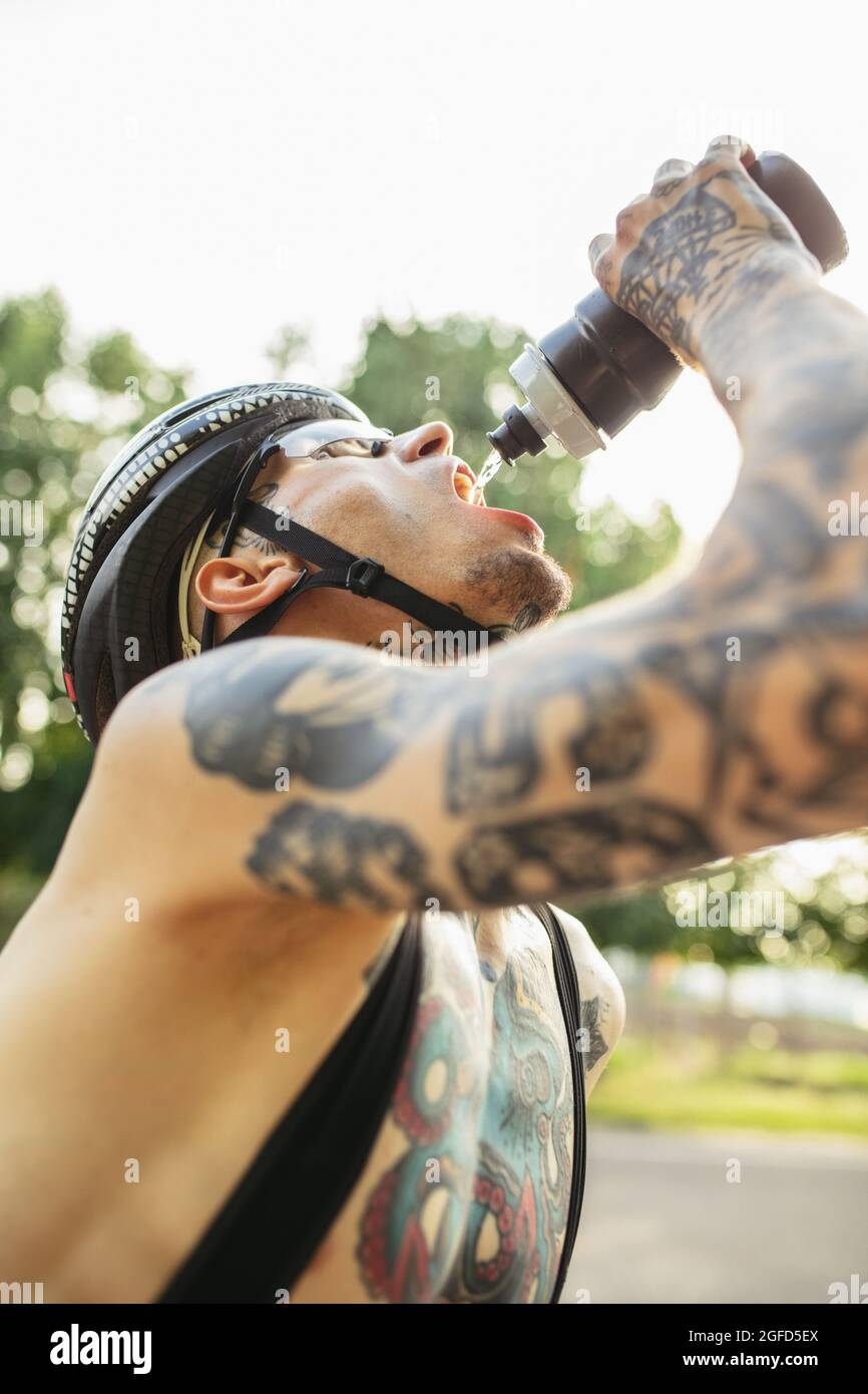 Stay hydrated. Young sportive cycling man drinking water Stock Photo ...