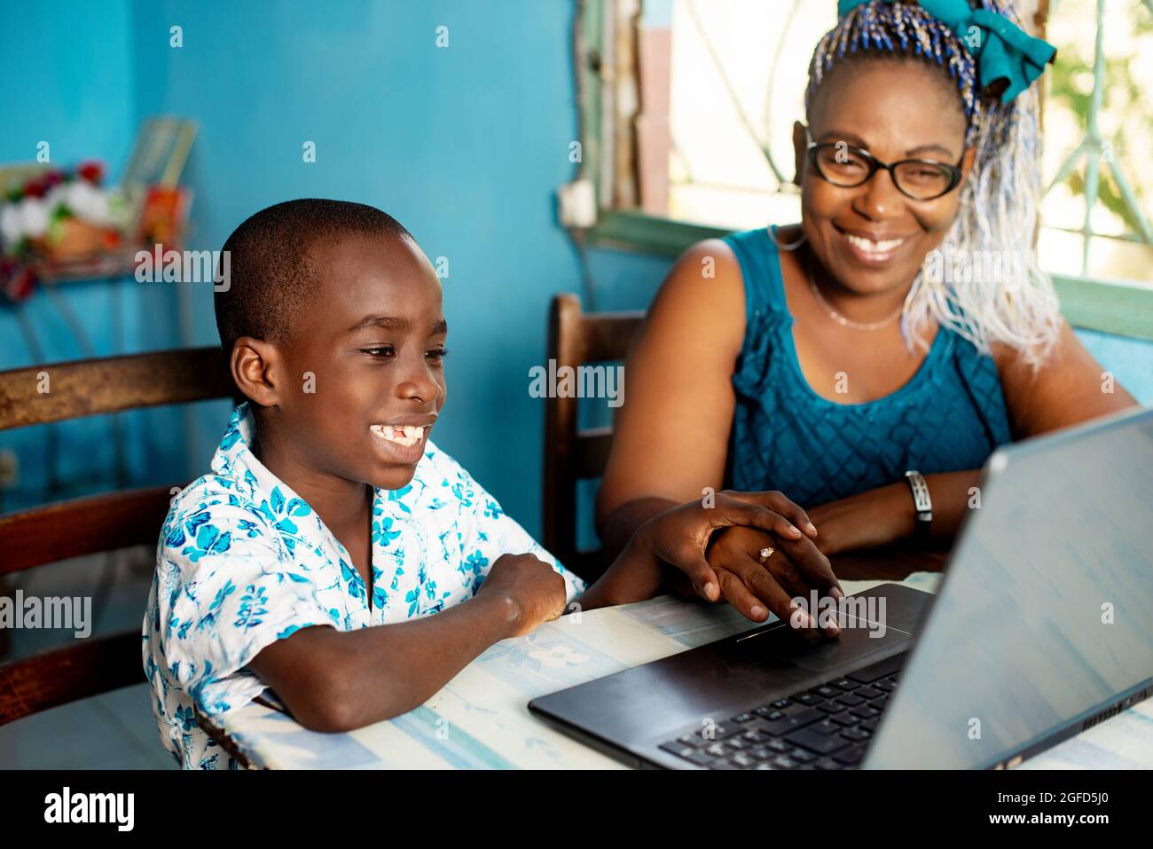 mother and son sitting together looking at the laptop while being ...
